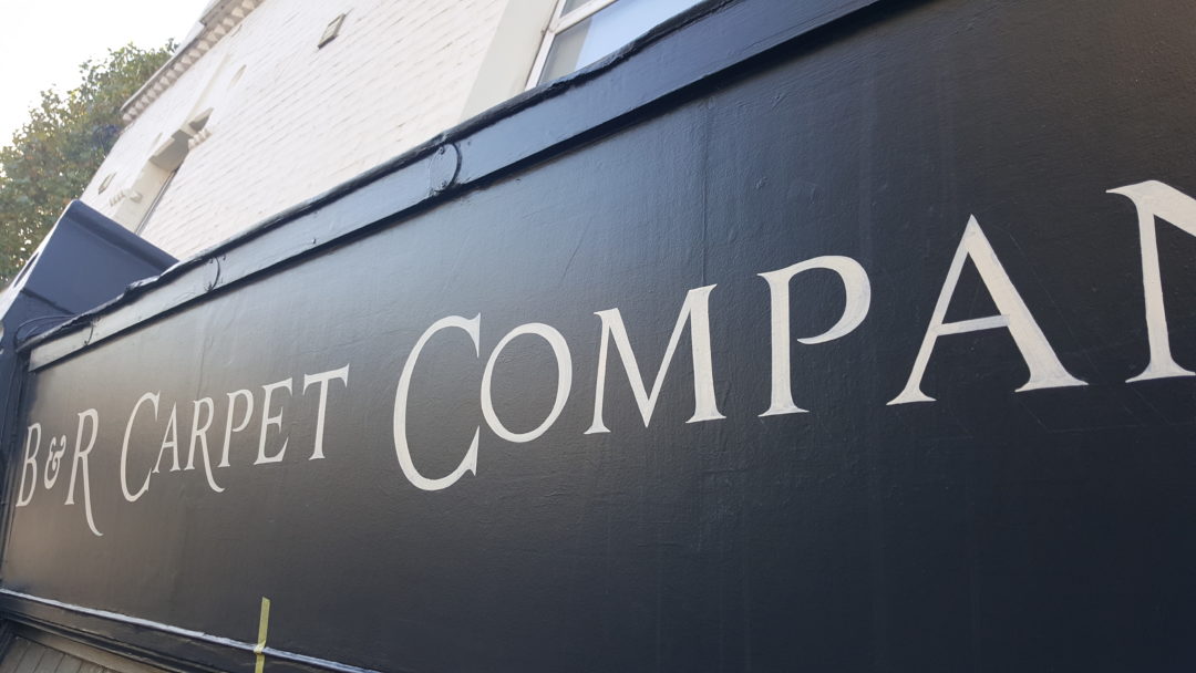 Shop sign writing on a corner building - Traditional Signs of London